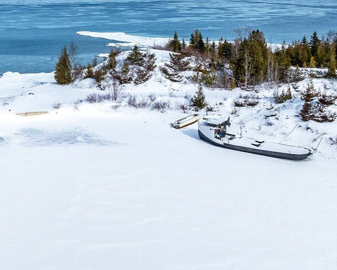 A lone boat waits patiently for spring on Lake Huron's frozen shore. Michigan winters create postcards at every turn.