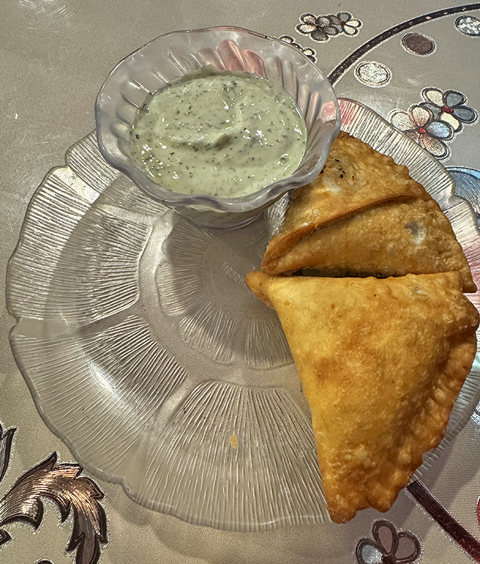 Golden samosas beside cooling raita&mdash;the perfect fried triangle that makes "just one more" an absolute impossibility.