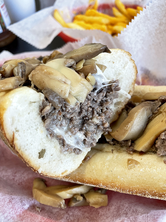 A mushroom cheesesteak cut in half reveals its soul—tender beef and melted cheese in perfect harmony.