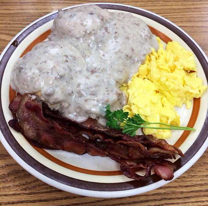 Two fluffy biscuits absolutely drowning in peppery sausage gravy with bacon and scrambled eggs completing this breakfast masterpiece.