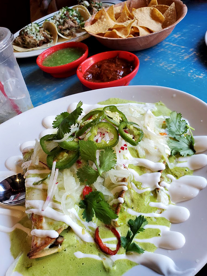 Green sauce cascades over enchiladas like a verdant waterfall, while jalape&ntilde;os and cilantro stand guard, ensuring every bite delivers its promised kick.