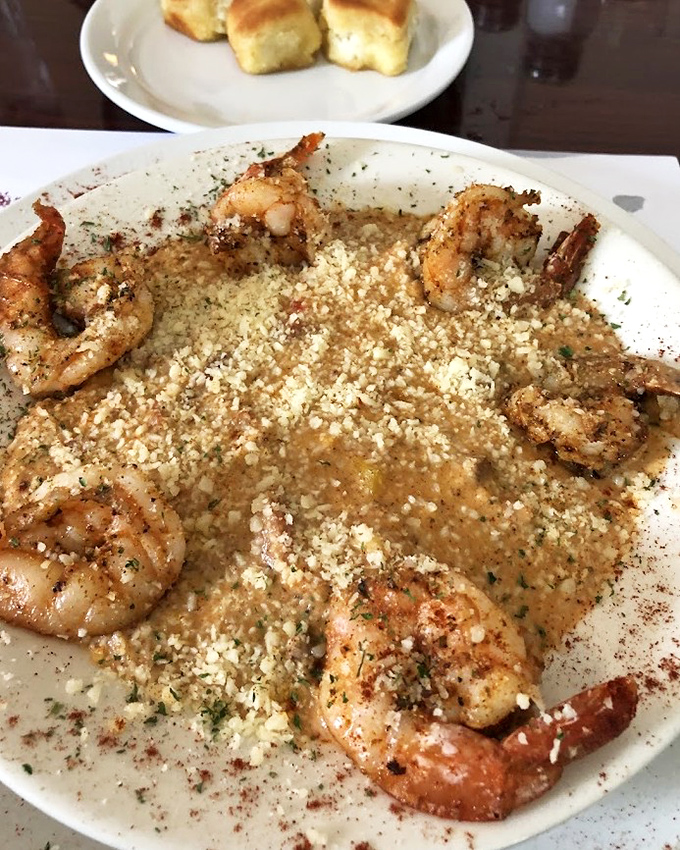 These aren't just shrimp and grits—they're tiny ocean jewels resting on a creamy bed of corn heaven, dusted with what appears to be parmesan confetti.