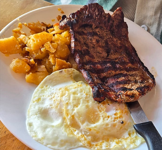 The breakfast trifecta: a juicy grilled steak, sunny-side-up egg, and golden home fries &ndash; morning fuel that would make champions jealous.