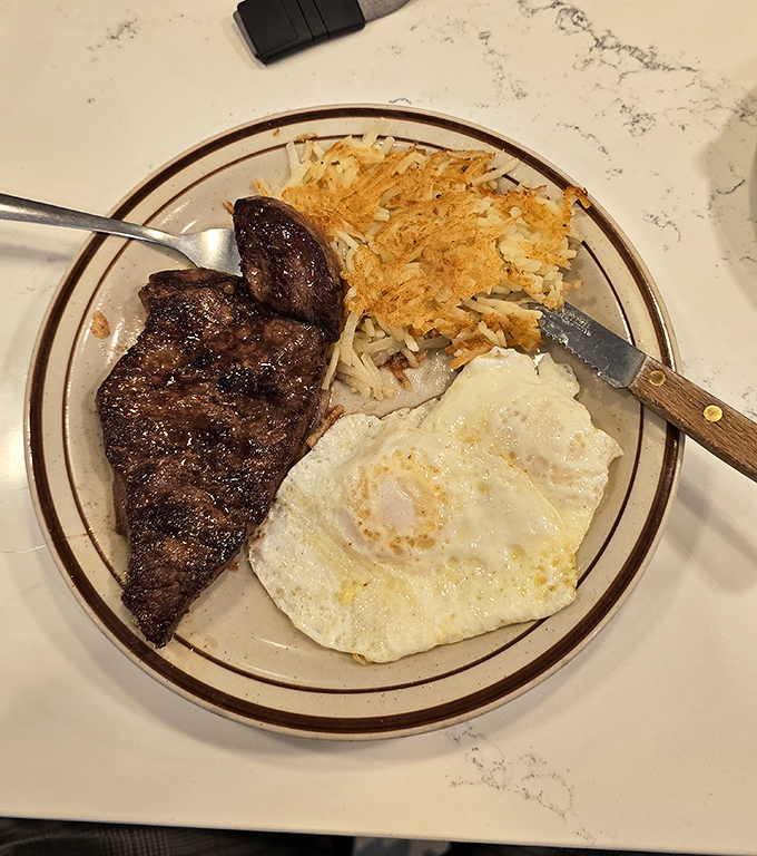 The breakfast trinity: perfectly seared steak, sunny-side-up egg, and hash browns crispy enough to make you forget about your diet resolutions.