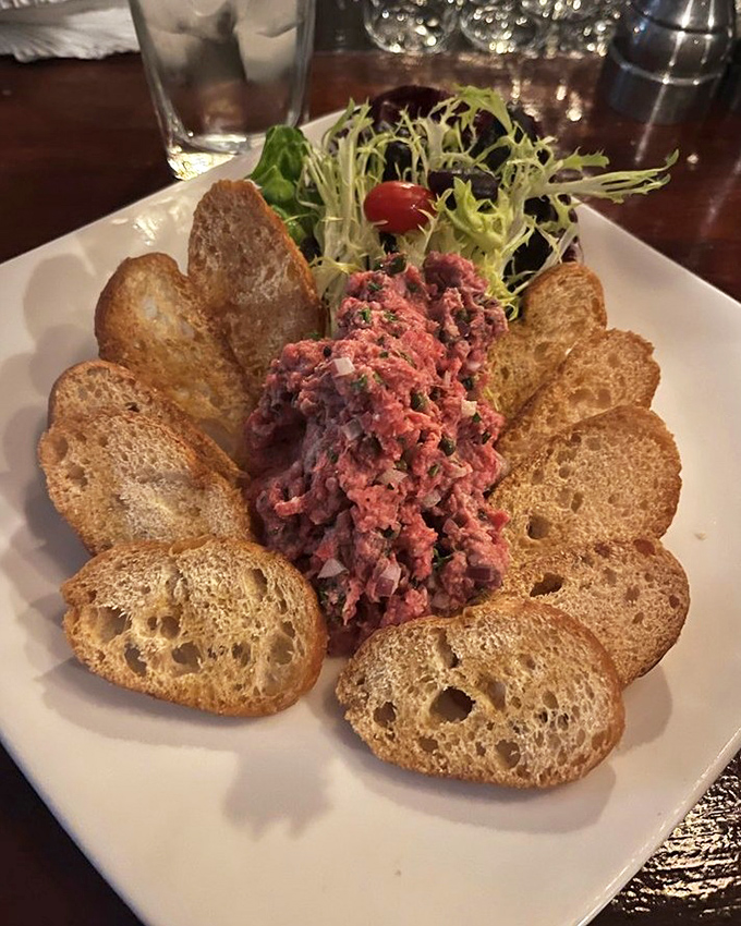 Steak tartare &ndash; where raw beef becomes an art form, surrounded by crisp toast points like a meaty sunflower in full bloom.