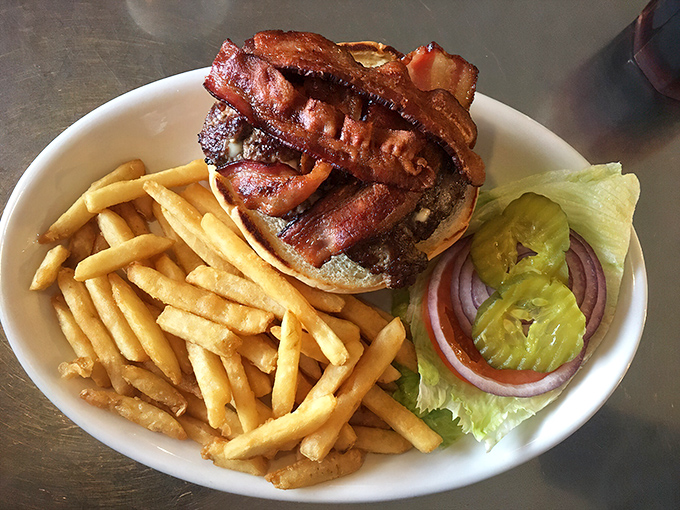 A burger that's clearly overachieving, with bacon stacked so high it needs its own zip code. The fries are just showing off at this point.