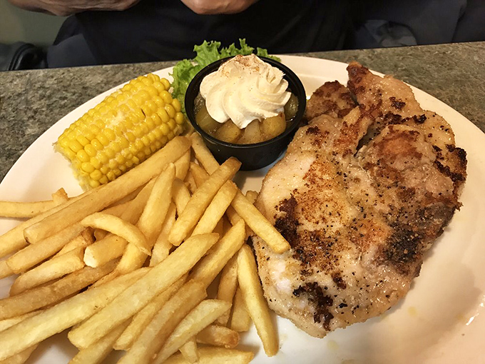 This isn't just dinner, it's edible architecture &ndash; golden pork chop, crispy fries, and corn on the cob creating the comfort food trifecta that dreams are made of.
