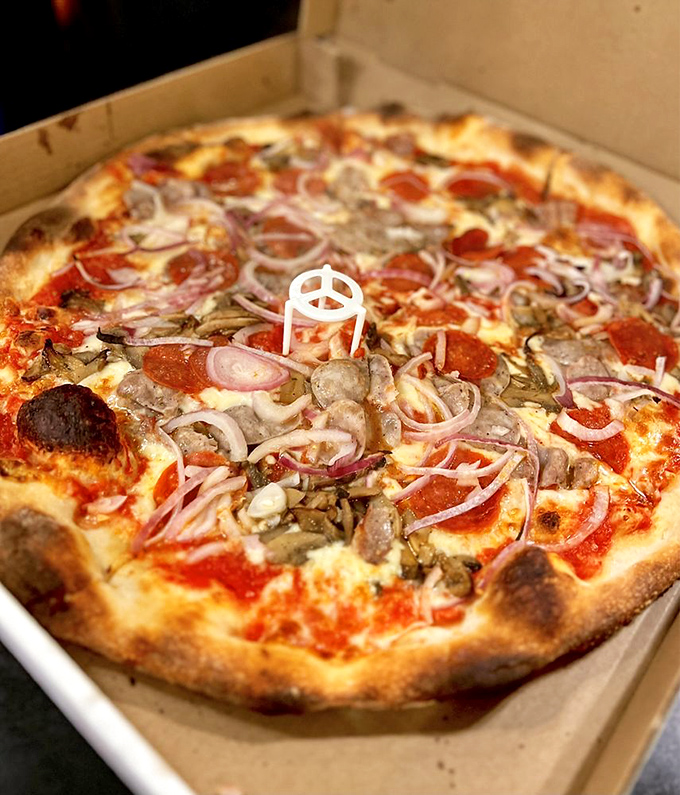 Supreme satisfaction in circular form. Those red onions and mushrooms aren't just toppings—they're the supporting actors in a Broadway pizza production.