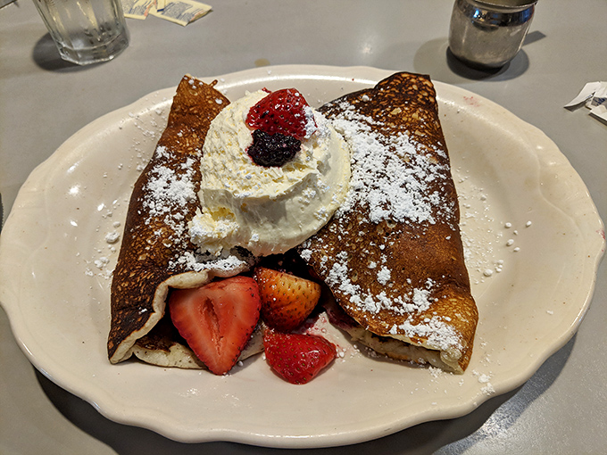 A crepe that's dressed for success with fresh berries, whipped cream, and enough powdered sugar to make your dentist wince delightfully.