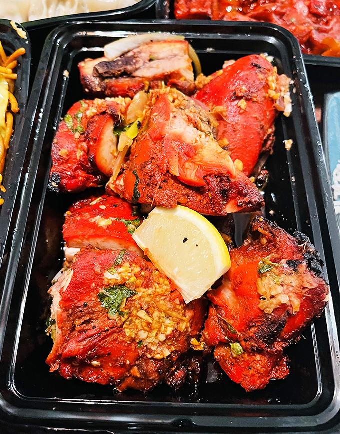 Tandoori chicken so vibrant it could direct traffic. That char speaks of intense heat and the lemon wedge isn't garnish—it's necessary balance.