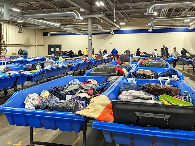 The archaeological dig of modern consumerism. Each blue bin contains layers of fashion history, forgotten electronics, and the occasional inexplicable treasure waiting for discovery.