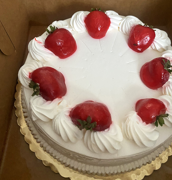 A strawberry-crowned cake that would make even the most dignified dinner guest fight for the last slice. Pure white frosting perfection!