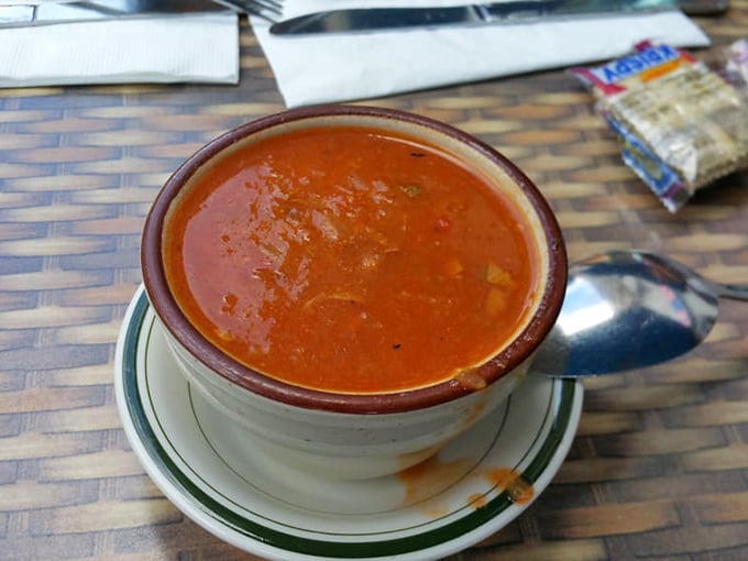 A bowl of liquid comfort! Tom's hearty vegetable soup arrives steaming in a classic ceramic cup, promising warmth that extends beyond just temperature.