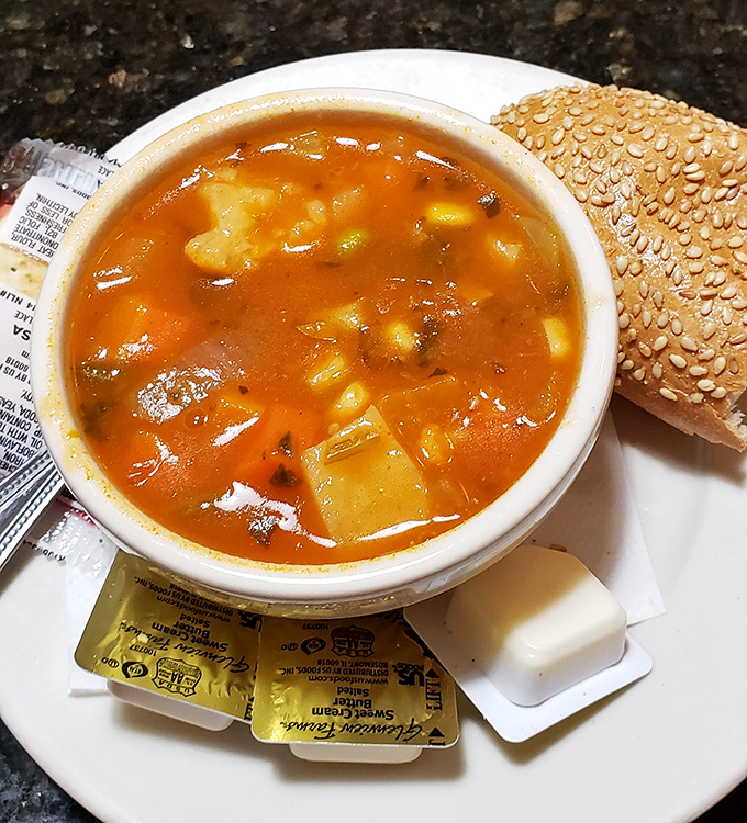 The legendary vegetable soup&mdash;chunky, hearty, and vibrant&mdash;sitting beside a sesame roll that's practically begging to be dunked.