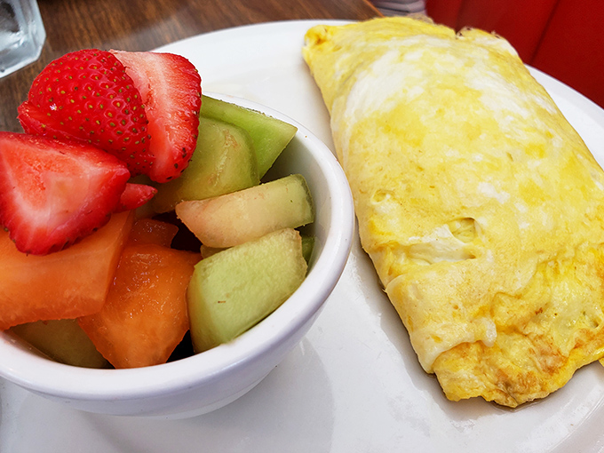 This isn't just an omelet&mdash;it's a golden envelope delivering a love letter of fresh vegetables alongside nature's perfect fruit salad.