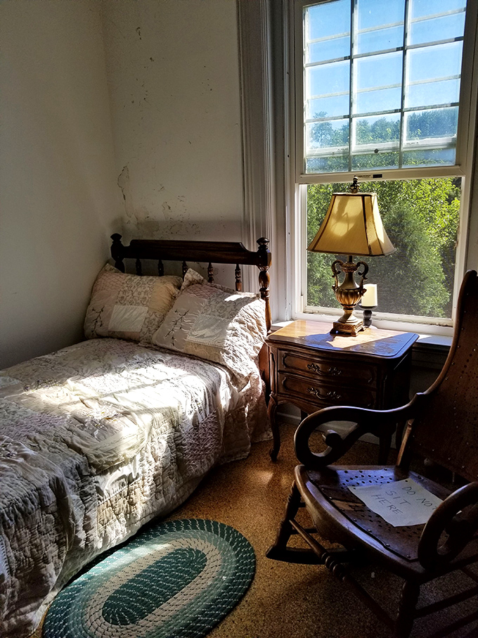 Sunlight streams through windows onto a bed where no one has slept for decades, creating a deceptively peaceful corner in this haunting building.