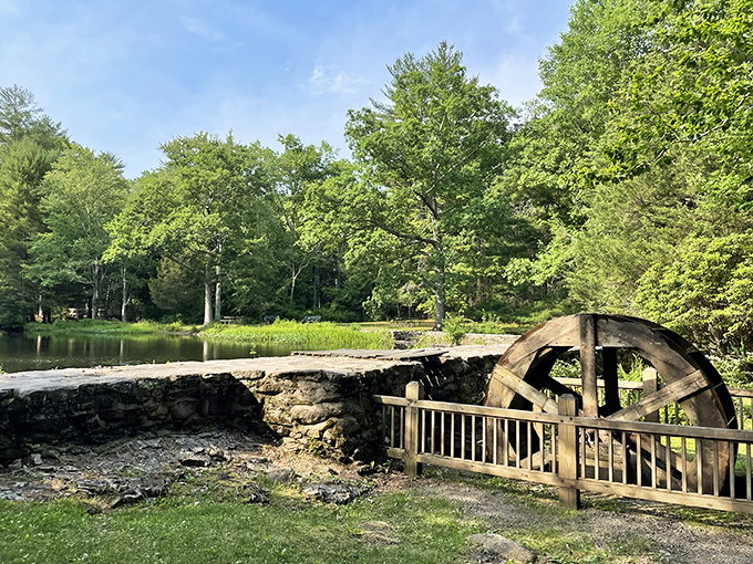 The water wheel stands as a rustic reminder of simpler times. Industrial history preserved in a setting worthy of a Rockwell painting.
