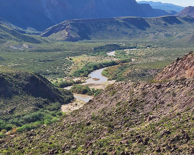 The winding river valley reveals itself like a plot twist in a geological novel, with water playing the unexpected hero in this desert tale.