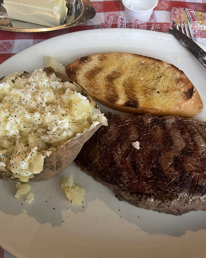 The loaded baked potato isn't just a side dish&mdash;it's a supporting actor deserving its own award, complementing the star ribeye in this meaty masterpiece.