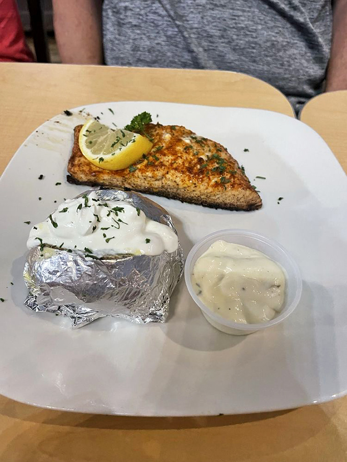 A perfectly blackened salmon fillet with a baked potato and housemade sauce proves seafood excellence exists hundreds of miles from any ocean.