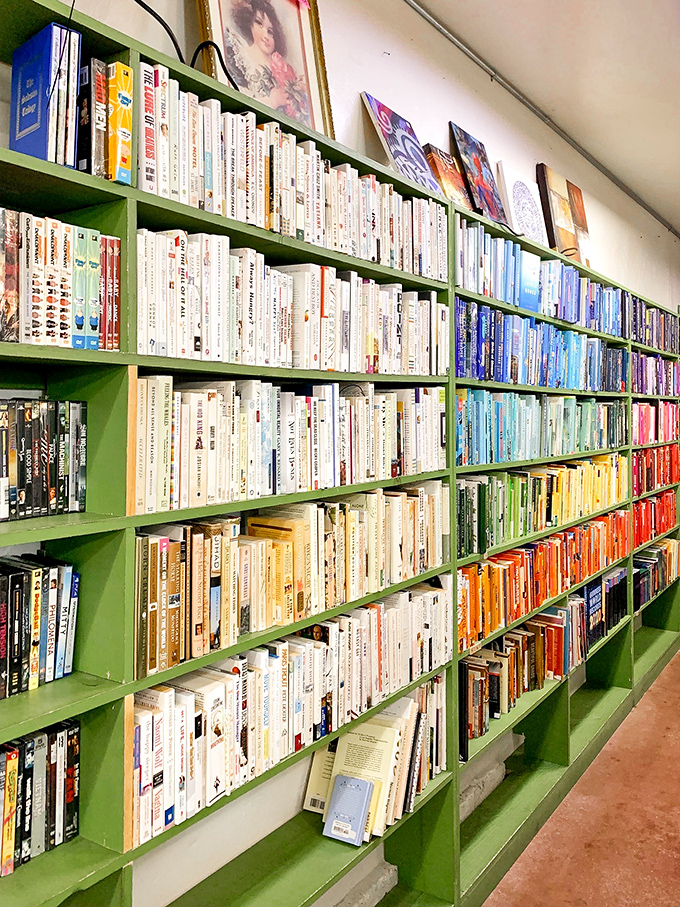 Color-coded books create a rainbow of literary possibilities. Somewhere on these shelves is the novel that will keep you up until 3 AM on a Tuesday. 