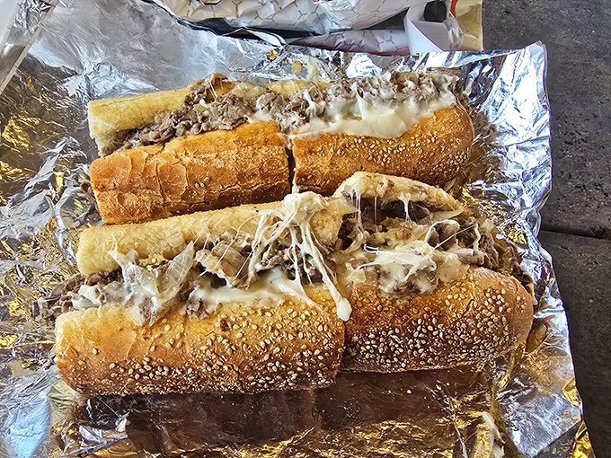 Cheese cascades over thinly chopped steak like a dairy waterfall, creating the kind of sandwich that haunts your dreams in the best possible way.