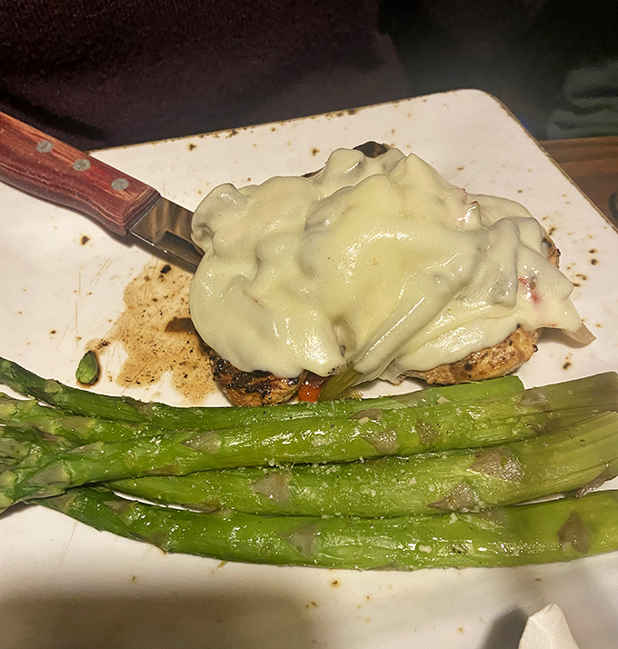 Melted cheese cascading over perfectly cooked chicken alongside vibrant asparagus spears &ndash; a plate that makes you want to slow down and savor every bite.