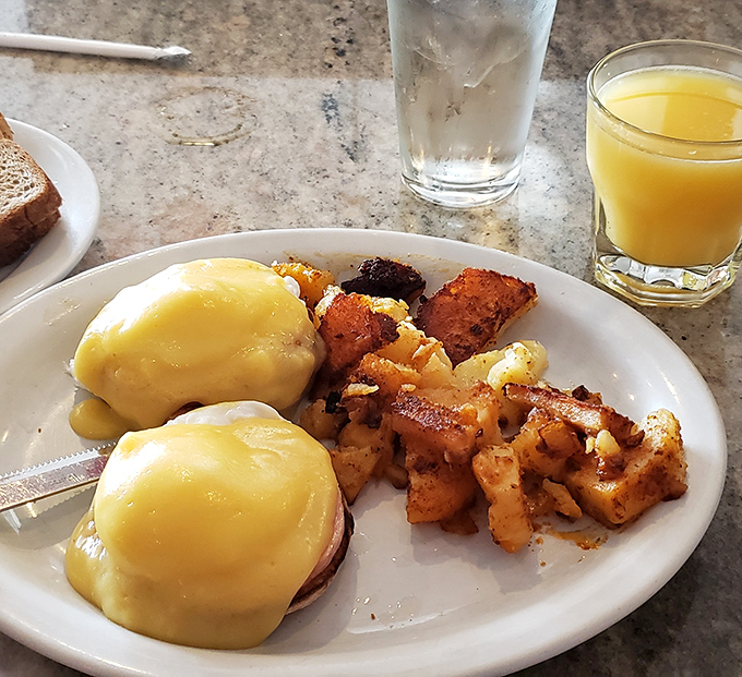 Eggs Benedict: where hollandaise sauce cascades over English muffins like a yellow waterfall of happiness. Those home fries deserve their own fan club.