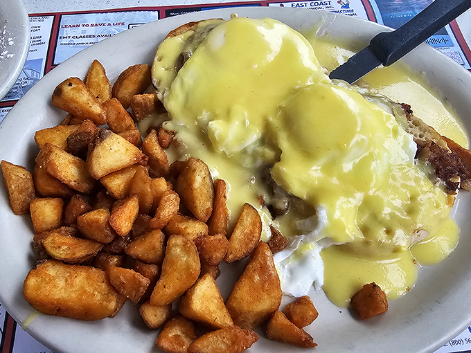 Hollandaise sauce cascading over eggs Benedict like a yellow waterfall of happiness, with home fries standing by for backup.