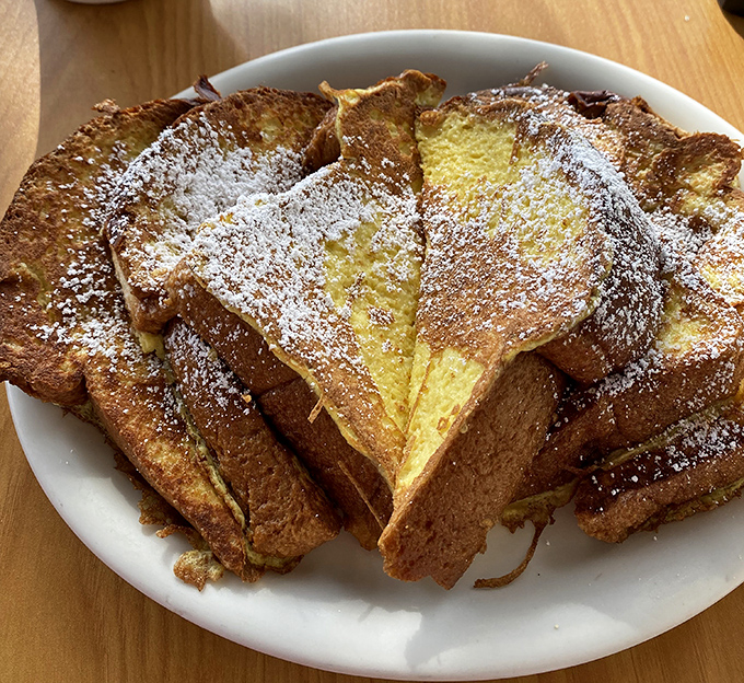 French toast that's achieved the impossible trifecta: crispy exterior, custardy interior, and enough powdered sugar to make your dentist wince approvingly.