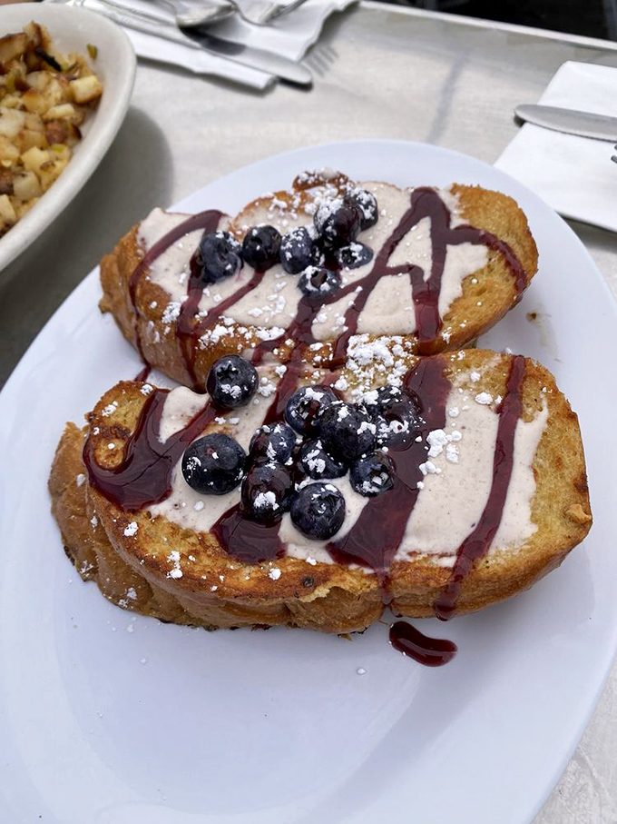 The legendary French toast arrives adorned with berries and cream—breakfast masquerading as dessert, and nobody's complaining.