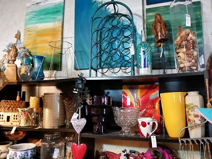 Colorful glassware catches the light while beach-inspired art transforms ordinary shelves into an impromptu coastal gallery.