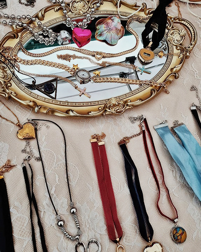 Vintage jewelry displayed on an ornate mirror&mdash;because even treasures deserve to admire themselves while waiting for new owners.