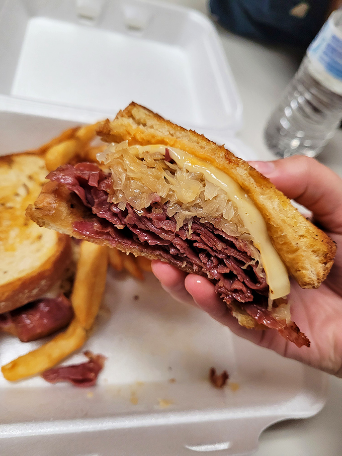 The Reuben sandwich in mid-bite glory&mdash;where corned beef, sauerkraut, and Swiss cheese perform a perfect harmony of flavors.