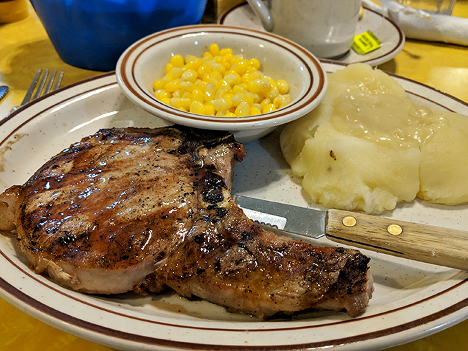 A perfectly grilled pork chop that would make even vegetarians pause for reflection, flanked by buttery mashed potatoes and sweet corn.