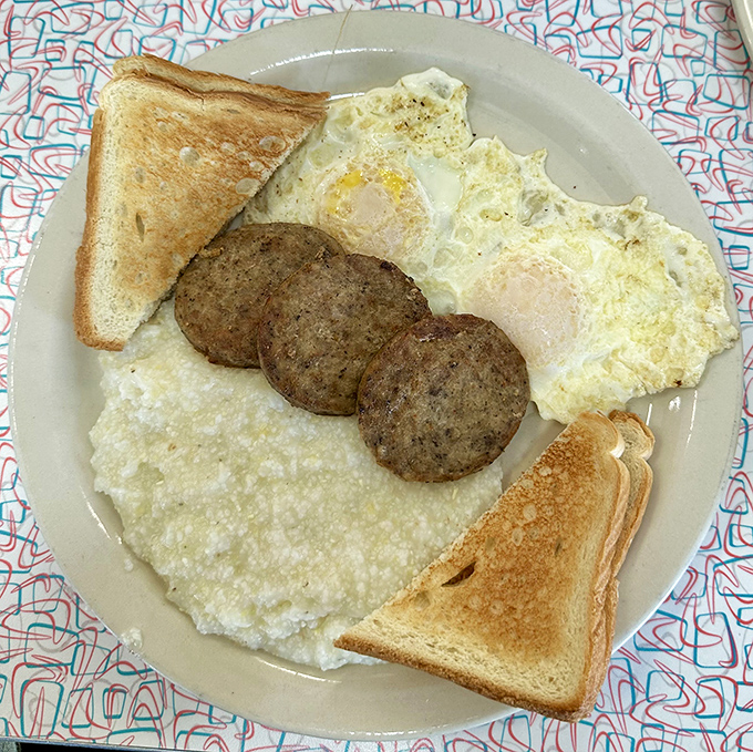 Breakfast's holy trinity: perfectly cooked eggs, savory sausage patties, and creamy grits. A plate that answers the eternal question, "What does morning happiness look like?"