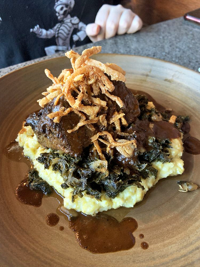 Short ribs so tender they practically surrender to your fork, nestled on creamy mash with crispy onions standing guard on top.