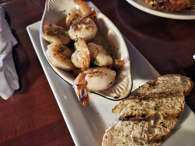 Plump shrimp that look like they just finished a spa day, served alongside crusty bread that's begging to soak up all that buttery goodness.
