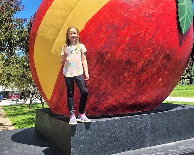 The universal roadside attraction measuring stick: "How tall am I compared to this enormous fruit?" A childhood rite of passage.
