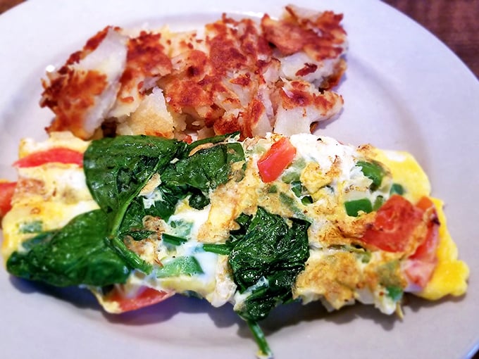 This isn't just breakfast &ndash; it's edible sunshine. Vibrant spinach and tomato nestled in fluffy eggs with crispy potatoes standing guard.