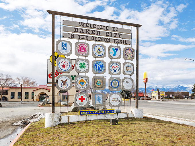 Baker City's welcoming sign showcases community pride with local organization emblems. This affordable town offers Old West charm without breaking your Social Security budget.