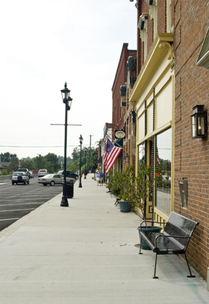 A bench sits ready for weary shoppers on Midway's sidewalk, where the pace is slow and nobody's in a hurry anyway.