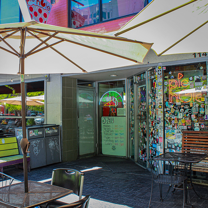 Sunlight illuminates Pie Hole's eclectic entrance, where every sticker tells a story of pizza pilgrimages past.