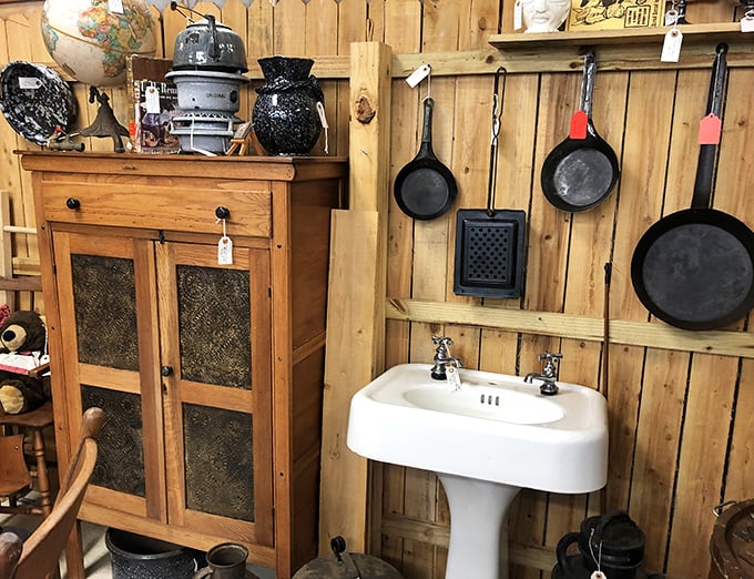 A vintage pedestal sink surrounded by cast iron pans, because kitchens used to have serious character.