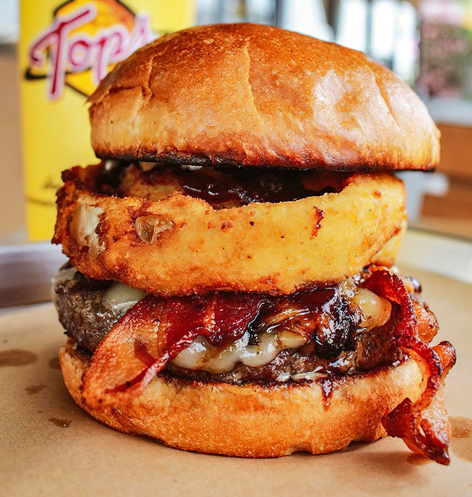 This isn't just a burger, it's architecture. The onion ring and bacon add structural integrity to this towering achievement.