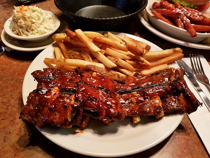 The rib rack arrives like meaty royalty on its throne of fries. That glistening sauce isn't just for looks&mdash;it's the barbecue equivalent of a perfect sunset.