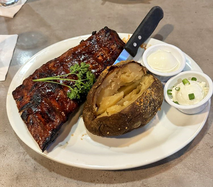 Baby back ribs with a smoke ring so perfect it could make a pitmaster weep, paired with a loaded baked potato that's a meal unto itself.