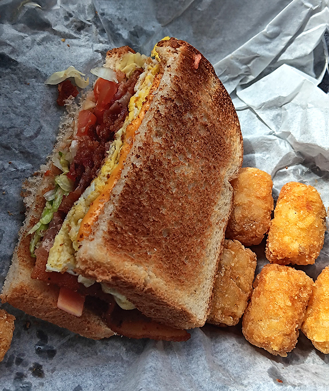 Breakfast meets lunch in this towering creation where eggs, bacon, and toast unite in a sandwich that would make morning meetings almost bearable.