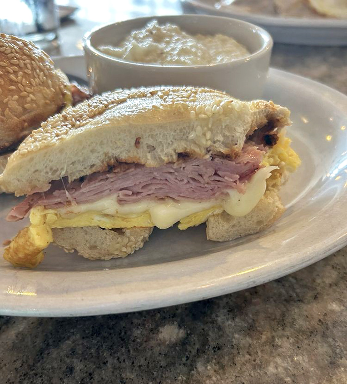 This sandwich doesn't need a fancy name—just ham, egg, and cheese on a sesame seed bun speaking the universal language of breakfast satisfaction.
