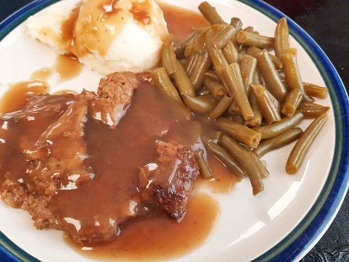 Baked steak swimming in gravy that should be declared a state treasure. The mashed potatoes aren't a side – they're an essential supporting character.